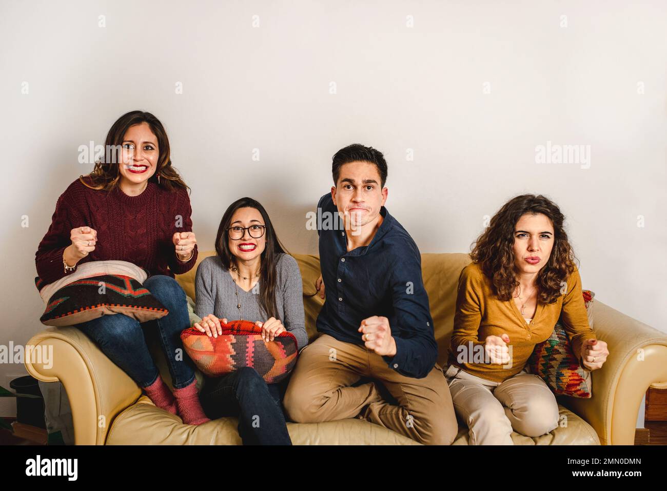 Group of scared friends gathering on sofa and watching horror movie ...