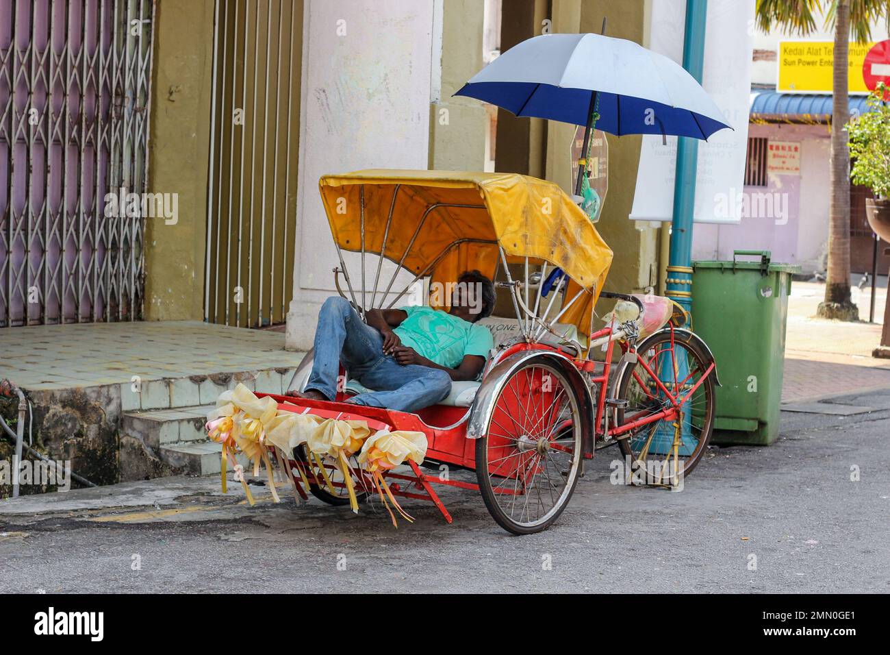 Georgetown, Penang, Malaysia - November 2012: A cycle rickshaw driver taking a nap in his ...