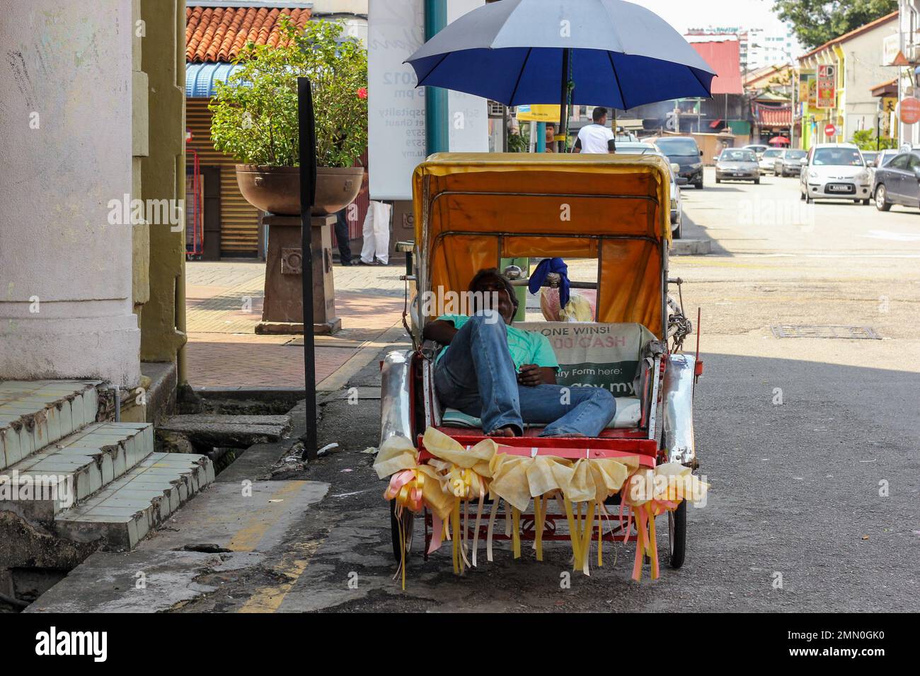 Georgetown, Penang, Malaysia - November 2012: A cycle rickshaw driver taking a nap in his ...
