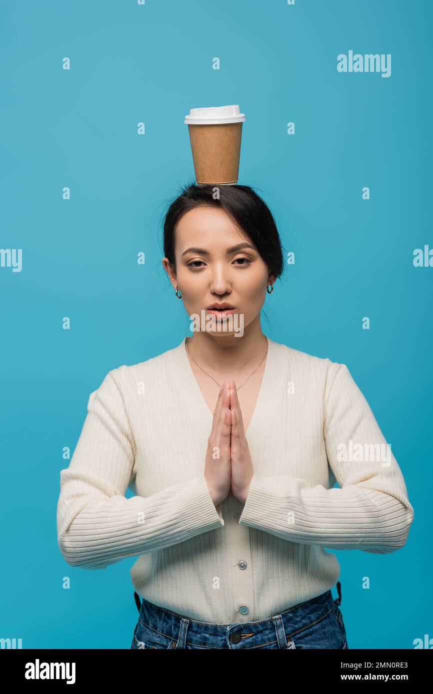 Asian woman with coffee to go on head doing praying hands gesture ...