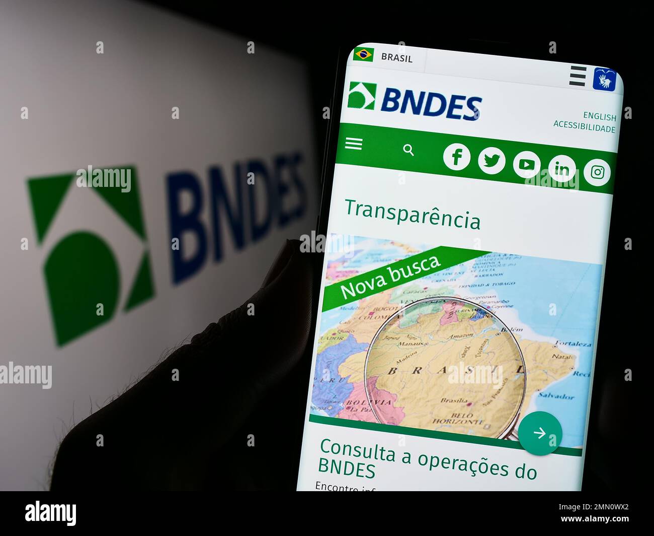 Person holding smartphone with webpage of Brazilian development bank ...