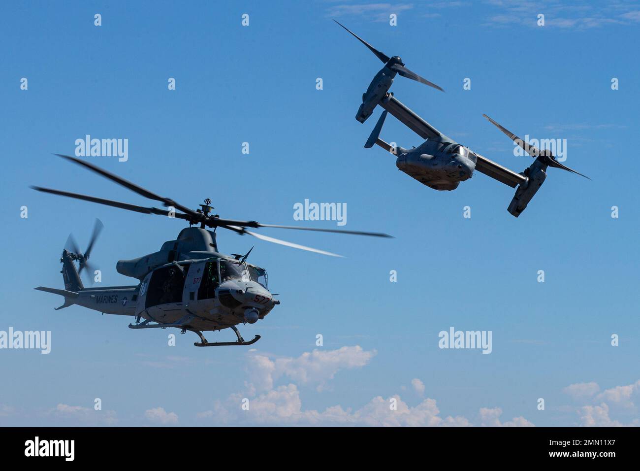 A UH-1Y Venom and a MV-22B Osprey flies above the flight line during ...