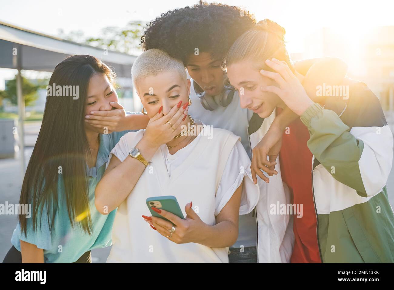 Cheerful group of friends looking smart phone surprised and excited ...