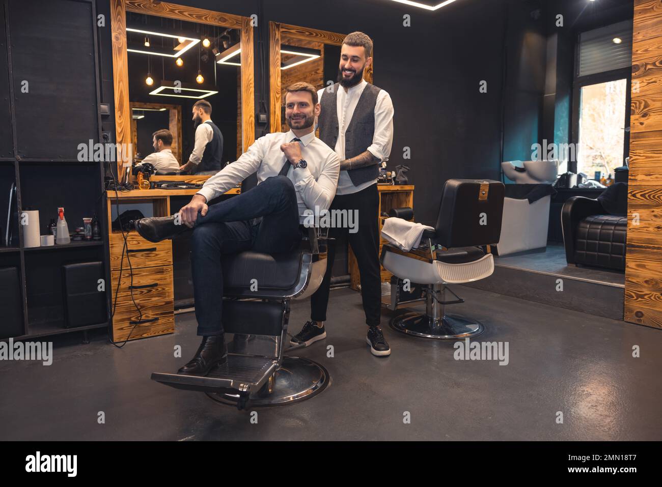 Elegant client sitting in a chiar in the barbershop Stock Photo - Alamy