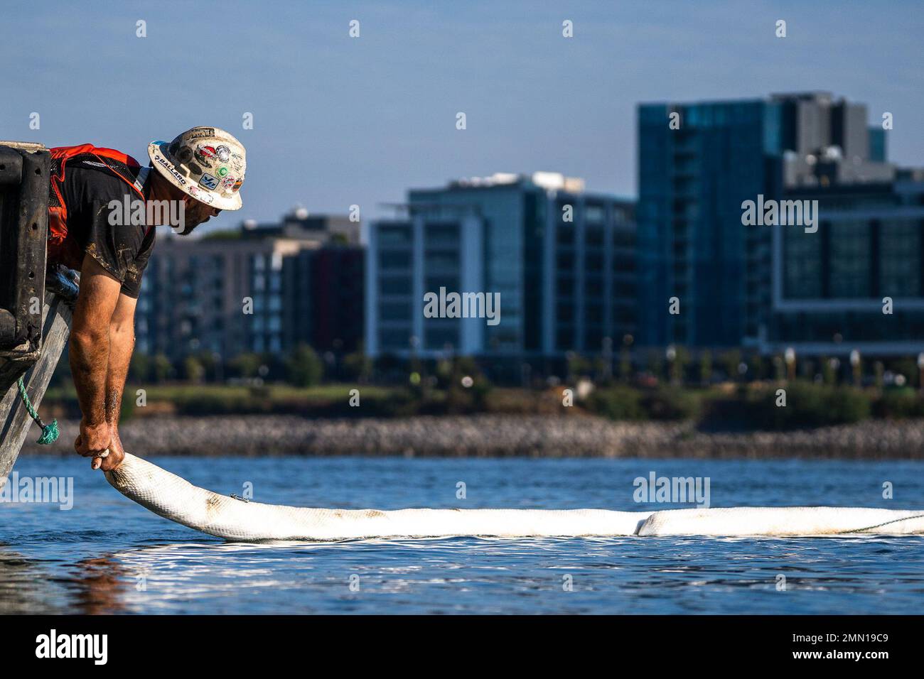 Employees from an oil spill response organization deploy containment ...