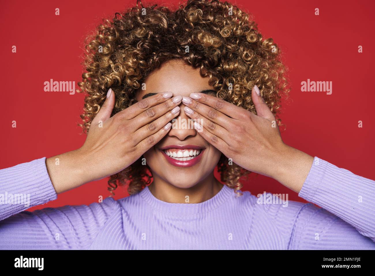 Young black woman with afro curls smiling at camera and covering her ...