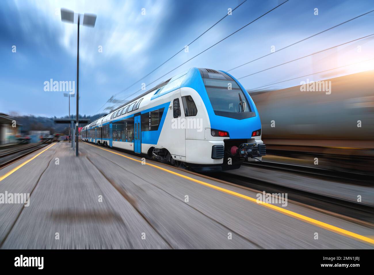 Blue high speed train in motion on the railway station at sunset Stock ...