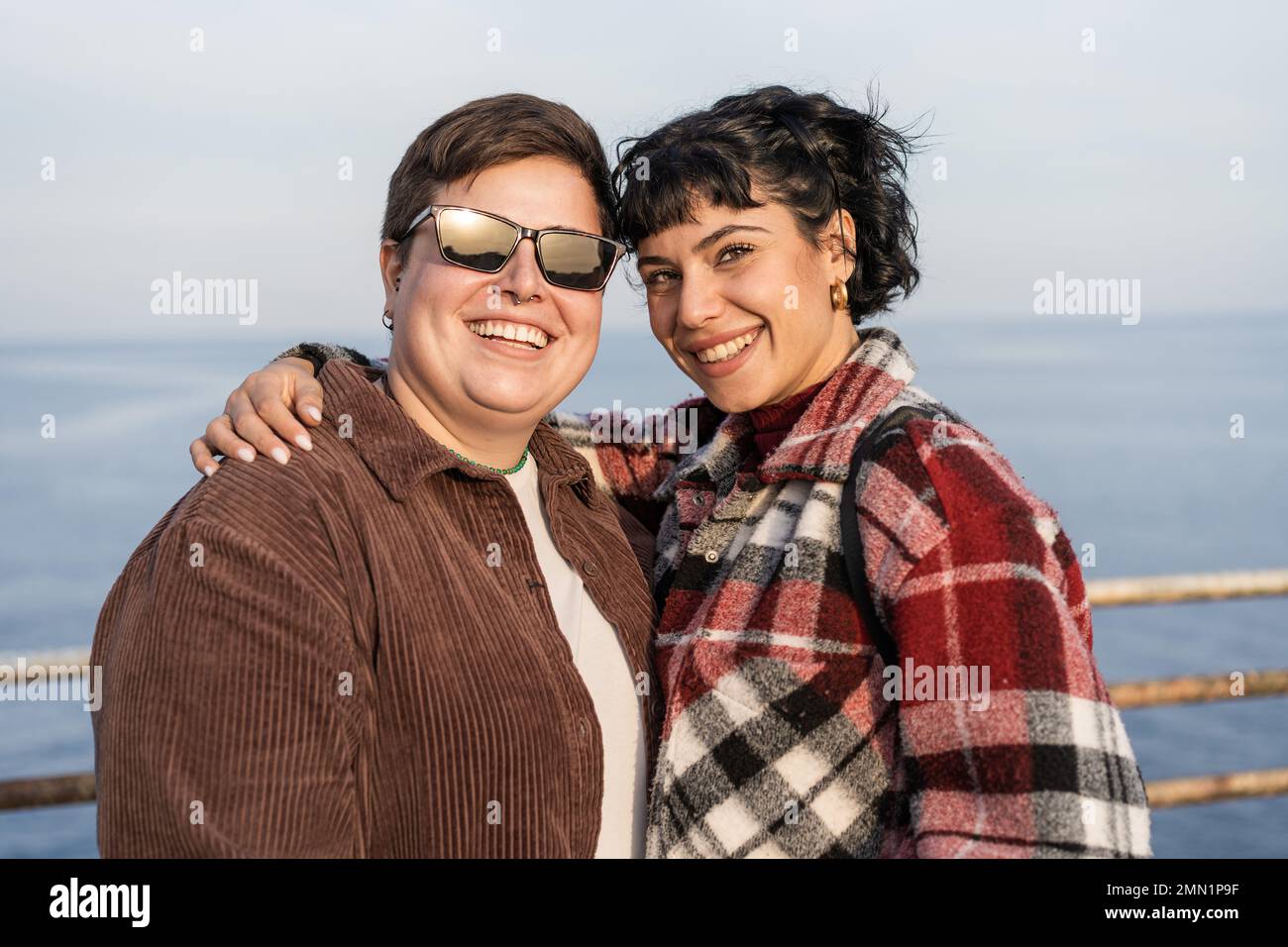Two young women, a brunette and a curvy non-binary person with a nose ...