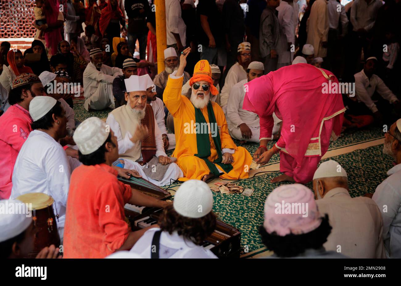 A devotee, in pink, offers money to a group of religious singers ...