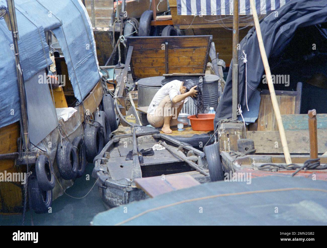 A young woman washes her hair over a basin, in the boat dwellers ...