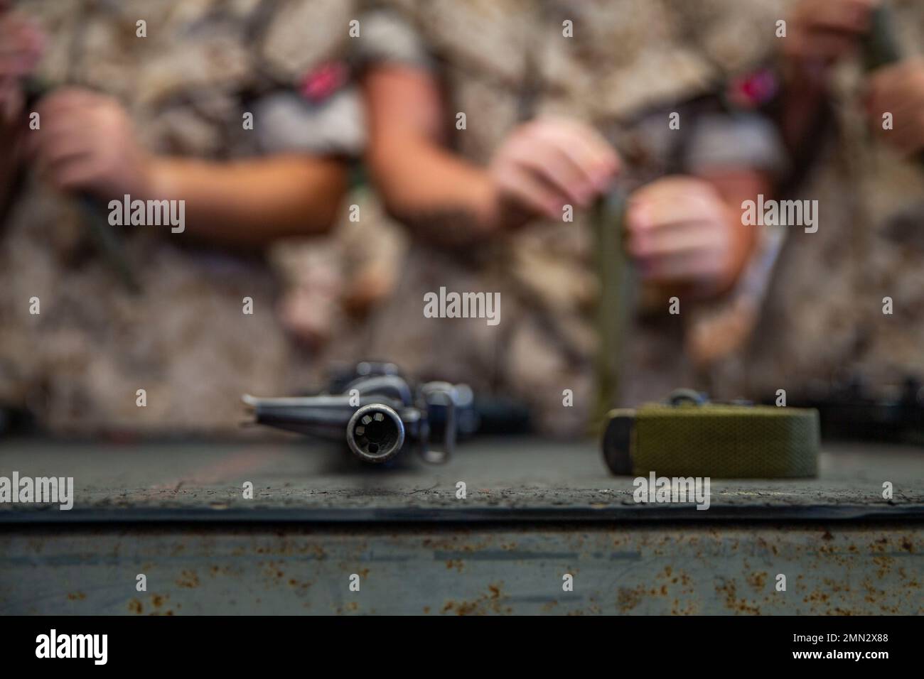 An M16A4 service rifle, and a sling lay on a table in front of a ...