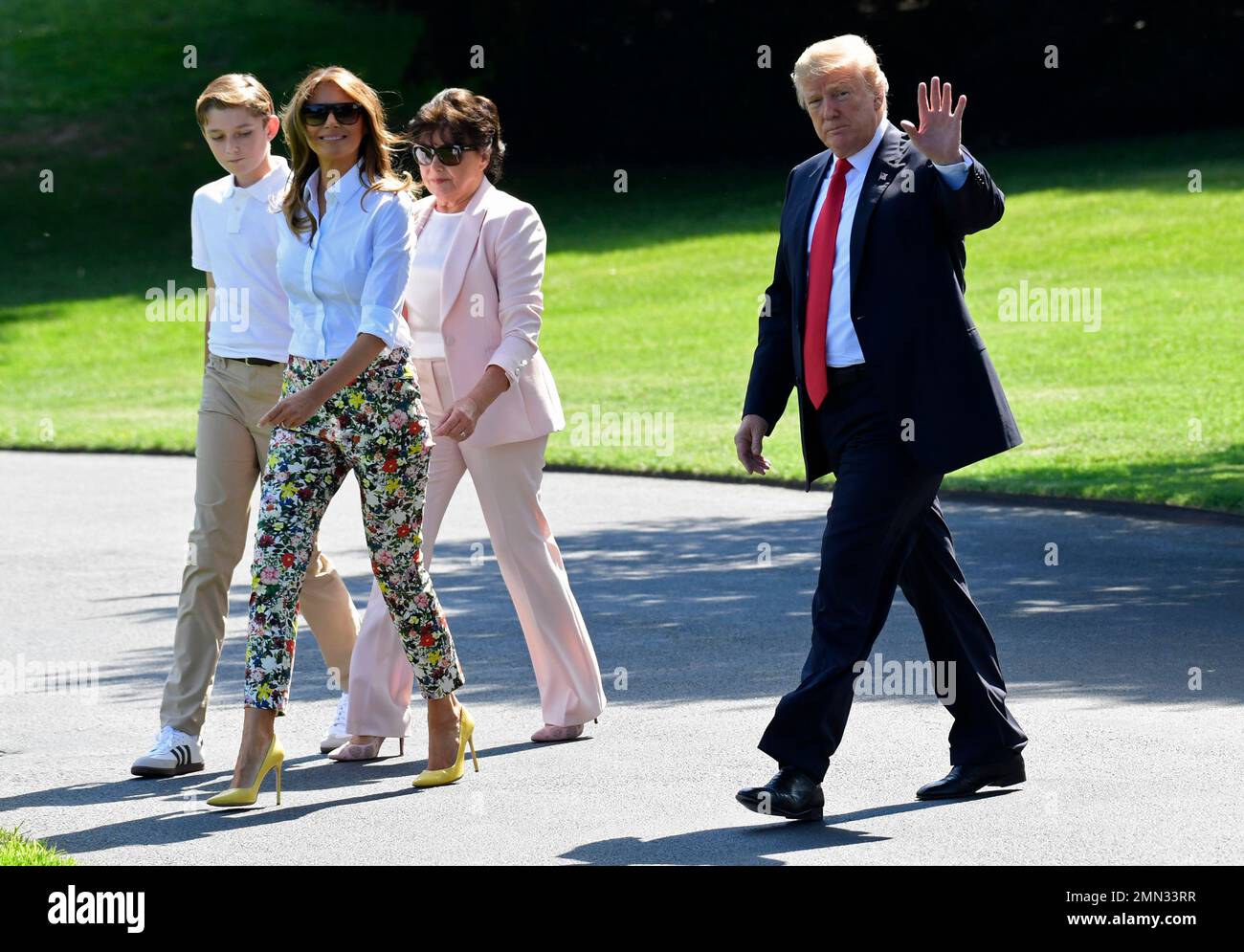 President Donald Trump, right, waves as he walks with first lady ...