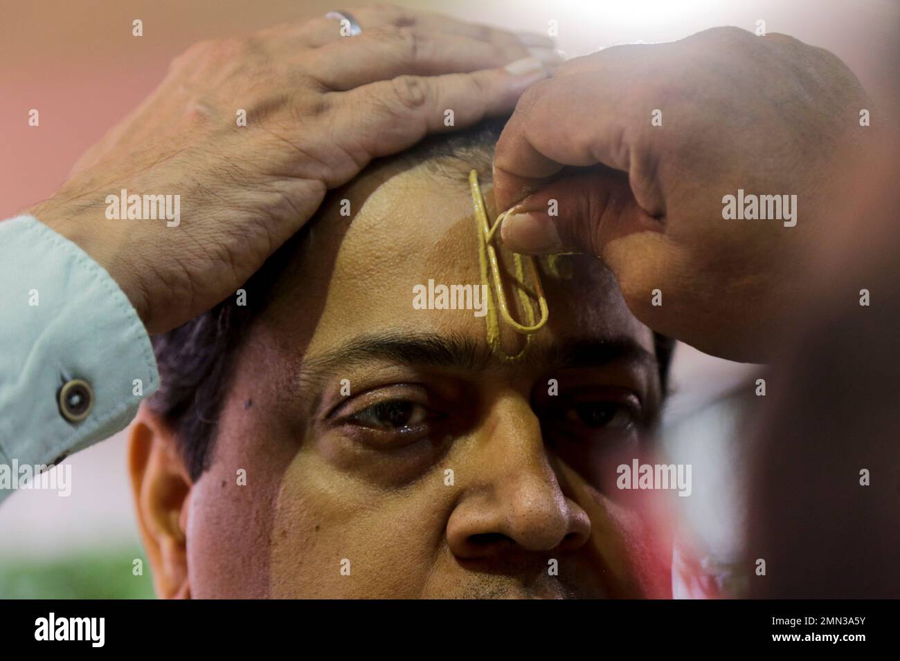 A Hindu priest puts a sacred mark on the forehead of a devotee during ...