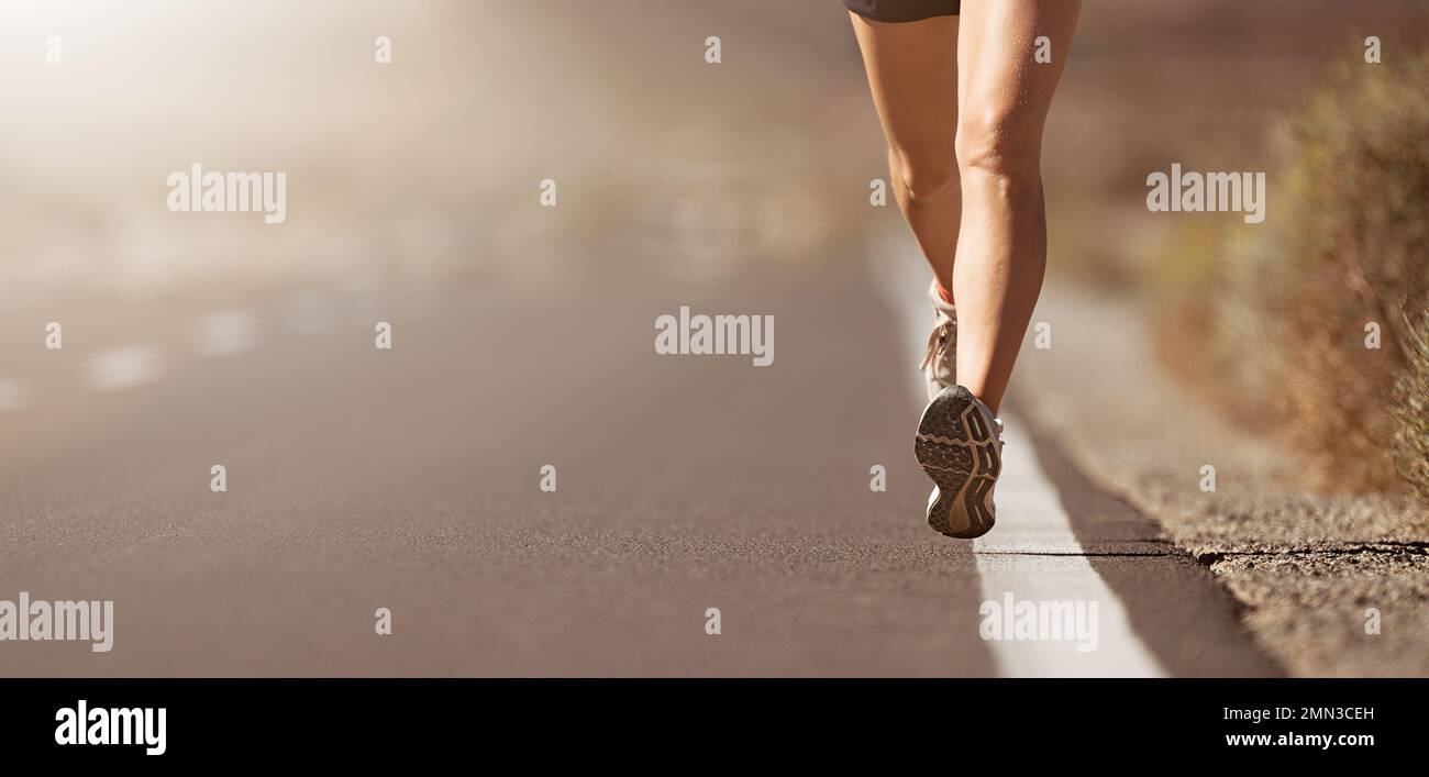Female legs close up of a woman running on a road with sports shoes ...