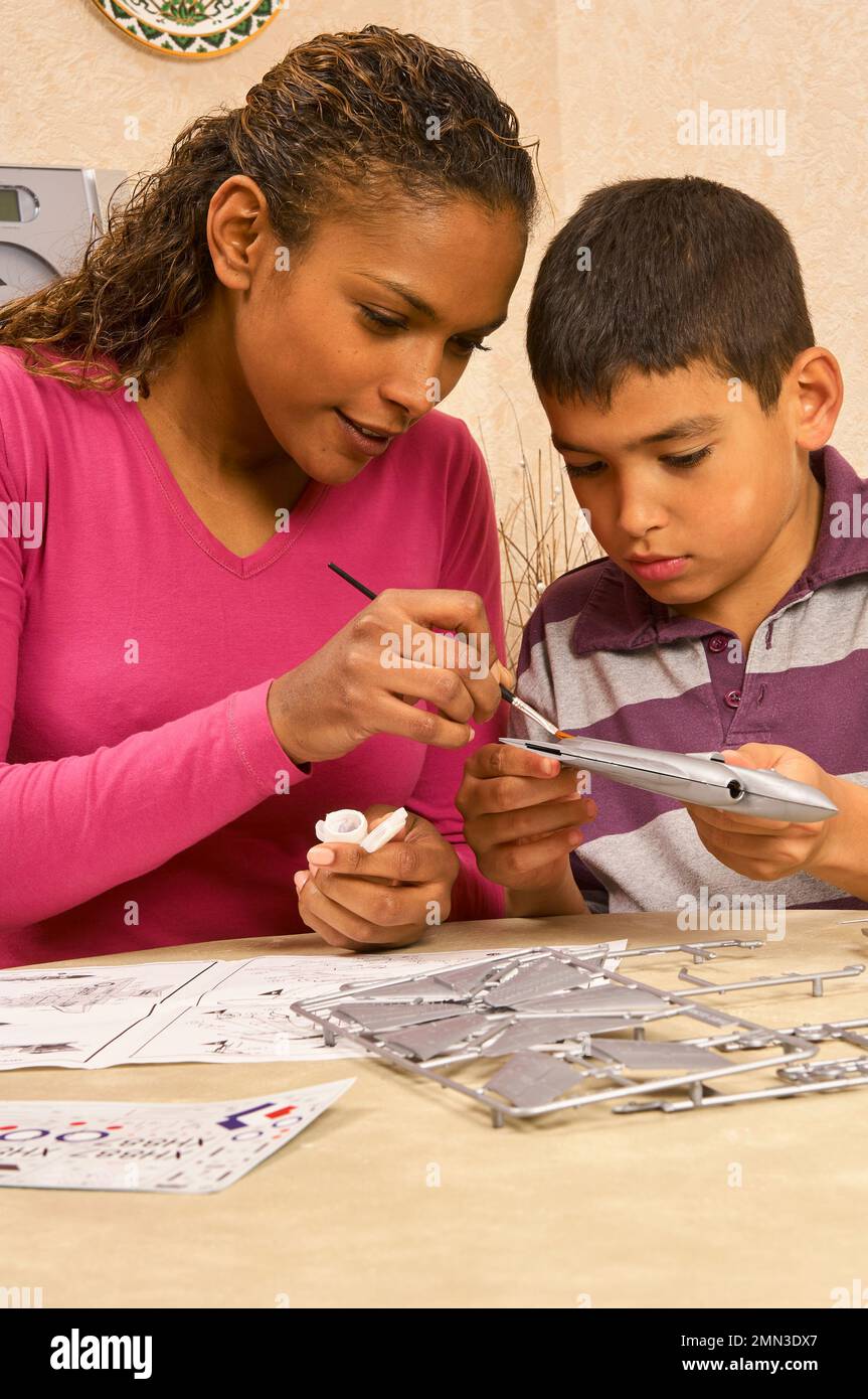 Young male boy and an adult female making a model toy aeroplane kit ...
