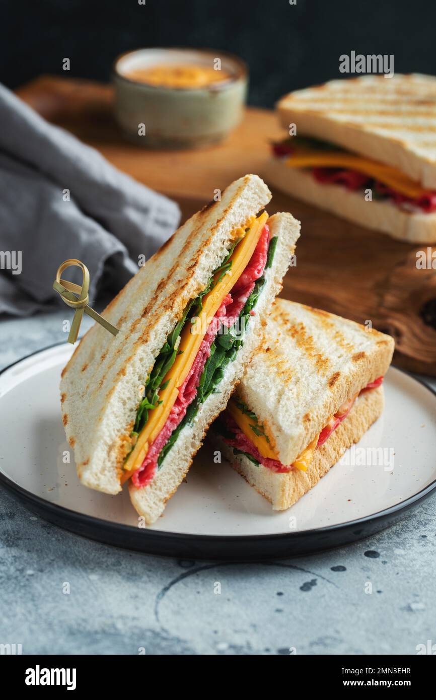 Two homemade sandwiches with sausage, cheese and arugula on a light ...