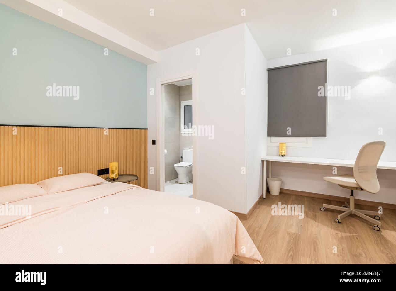 View of bedroom with large bed, work area with white wooden table and ...