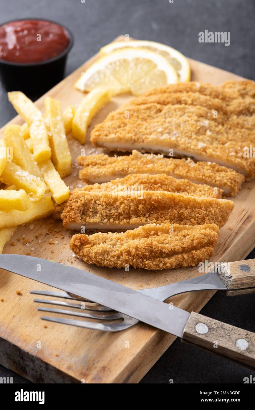 Wiener schnitzel with fried potatoes on black background Stock Photo ...