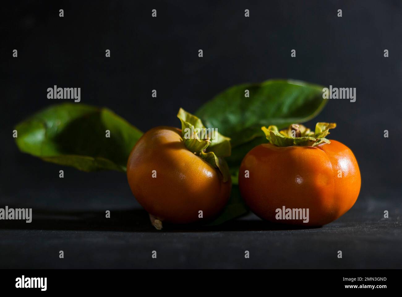 Ripe orange persimmons ready to eat on dark background in horizontal ...
