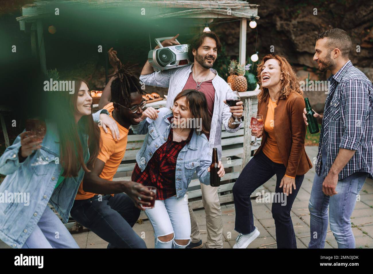 A group of friends enjoys dancing and drinking beers, cocktails, and ...