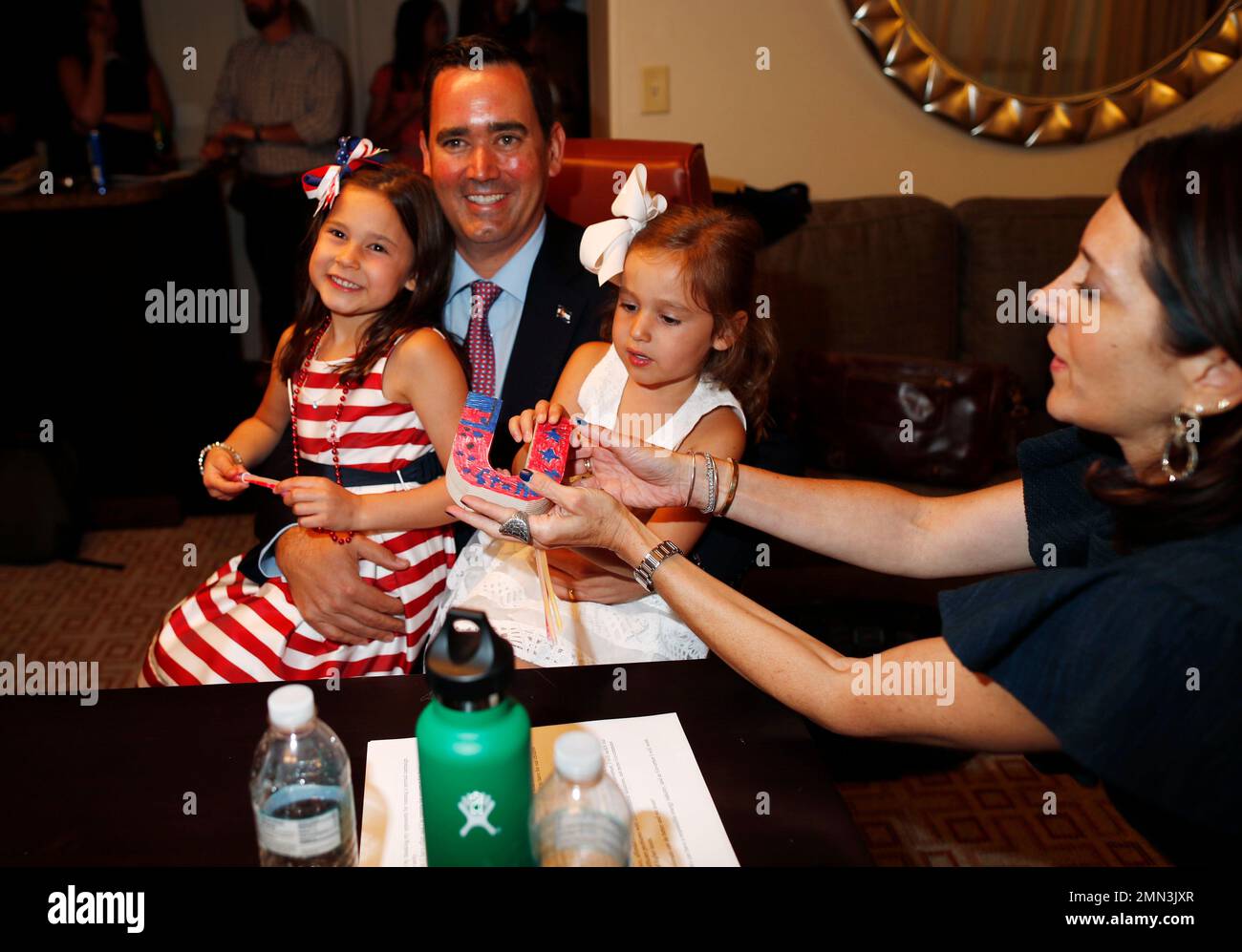 Walker Stapleton, second from left, holds his two daughters, 7-year-old Colette, and 4-year-old ...