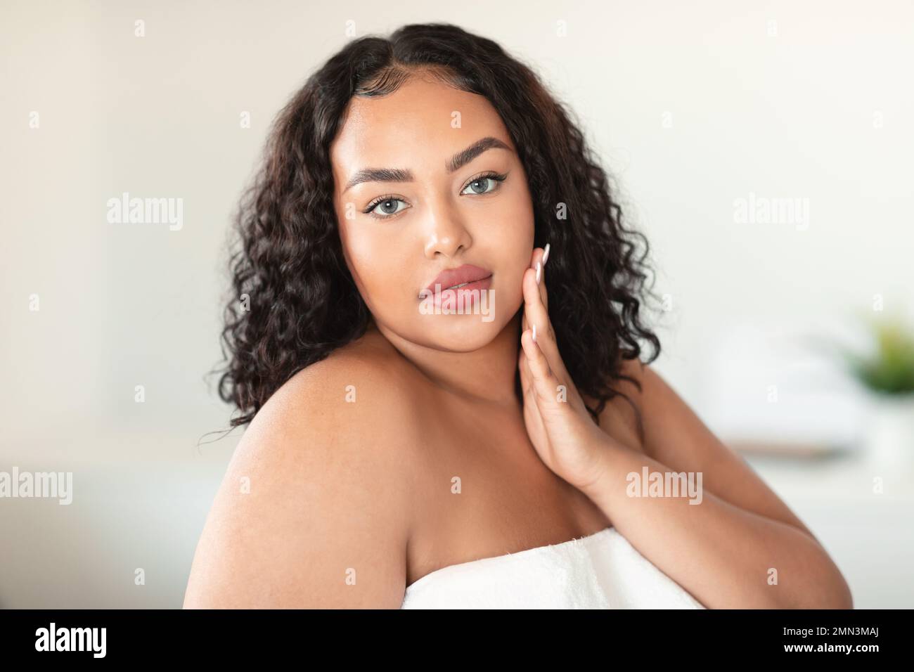 Portrait of beautiful bodypositive lady touching her cheek, enjoying ...