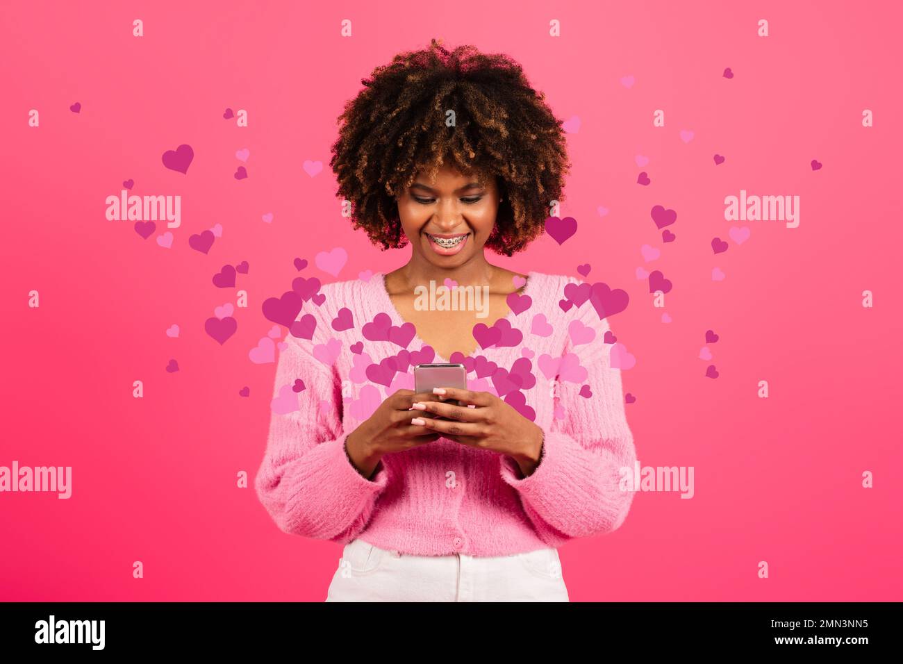 Glad young black curly lady with braces typing on phone with many ...