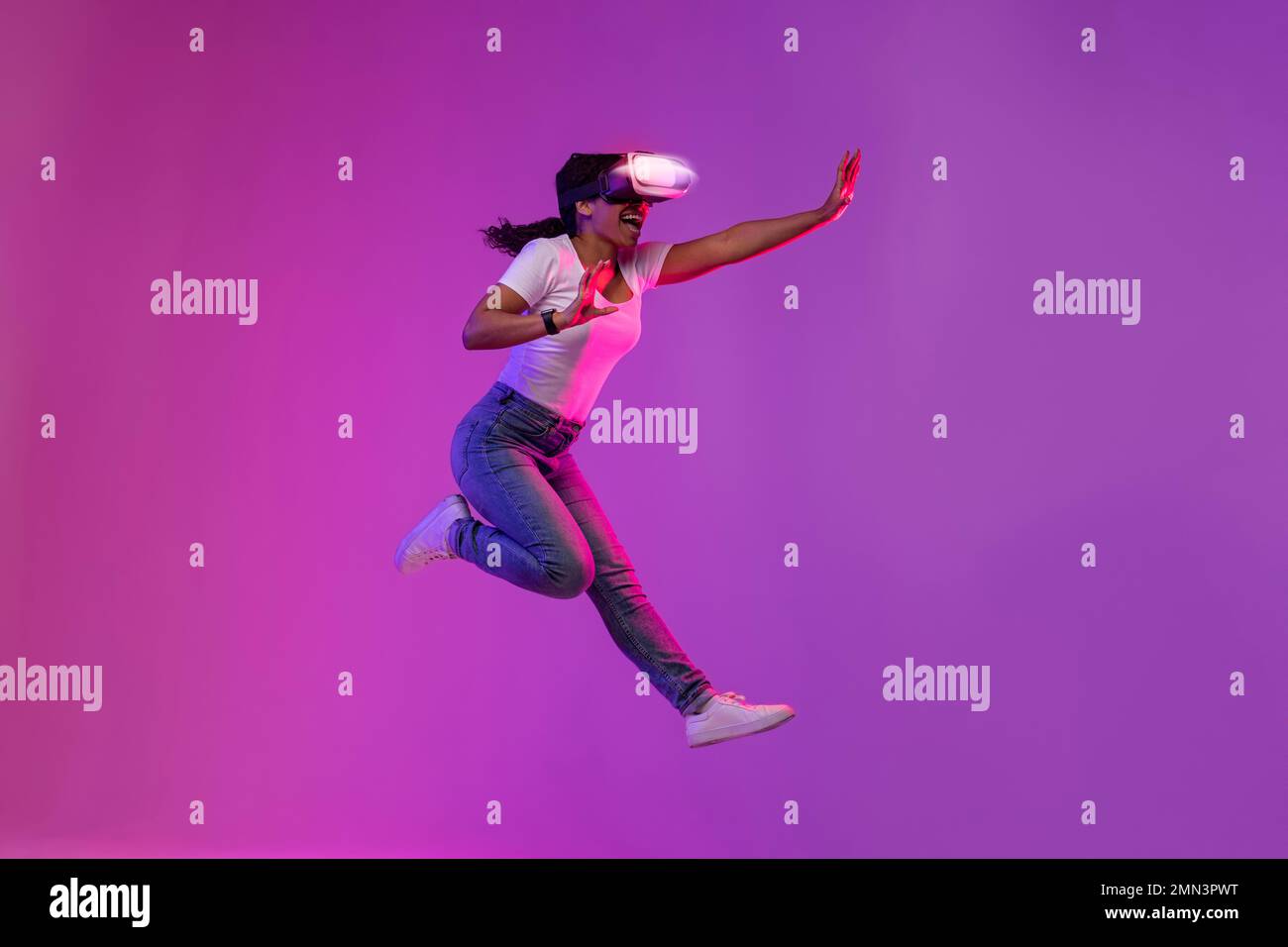 Excited Young Black Female Wearing Glowing VR Glasses Jumping In Neon ...