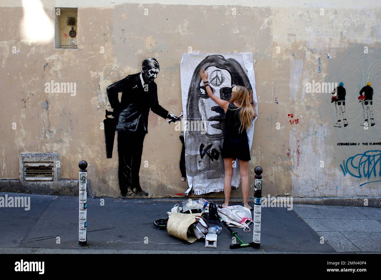 Artist Konny Steding puts up a poster partially covering a graffiti ...