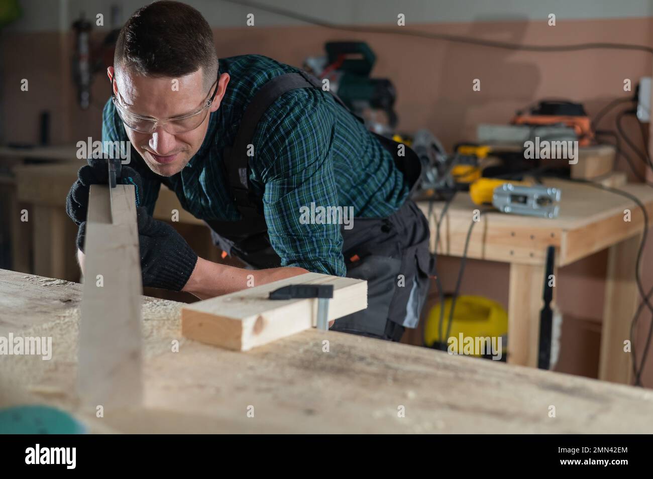 Carpenter measures a wooden board while working in a workshop Stock ...