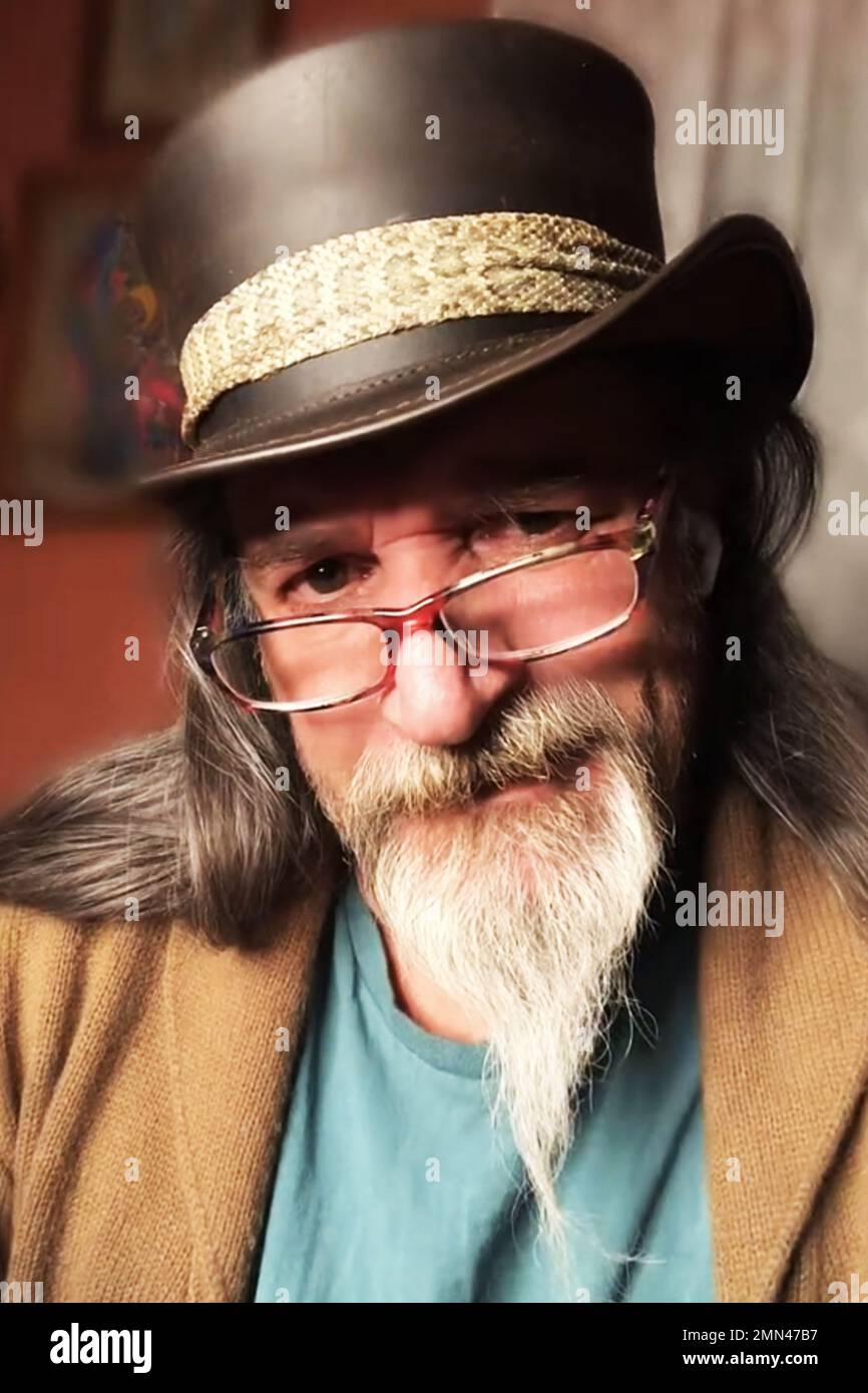 Elderly person with long beard and vintage hat poses for a portrait ...