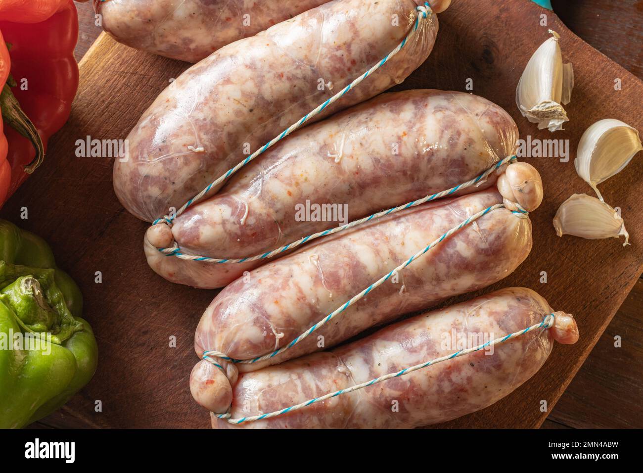 Detail of raw chorizos on a cuting board , typical Argentine sausages made with mixed pork and ...