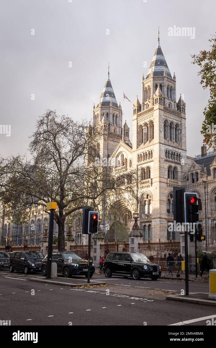 The facade of the Natural History Museum lit by the setting sun as cars ...