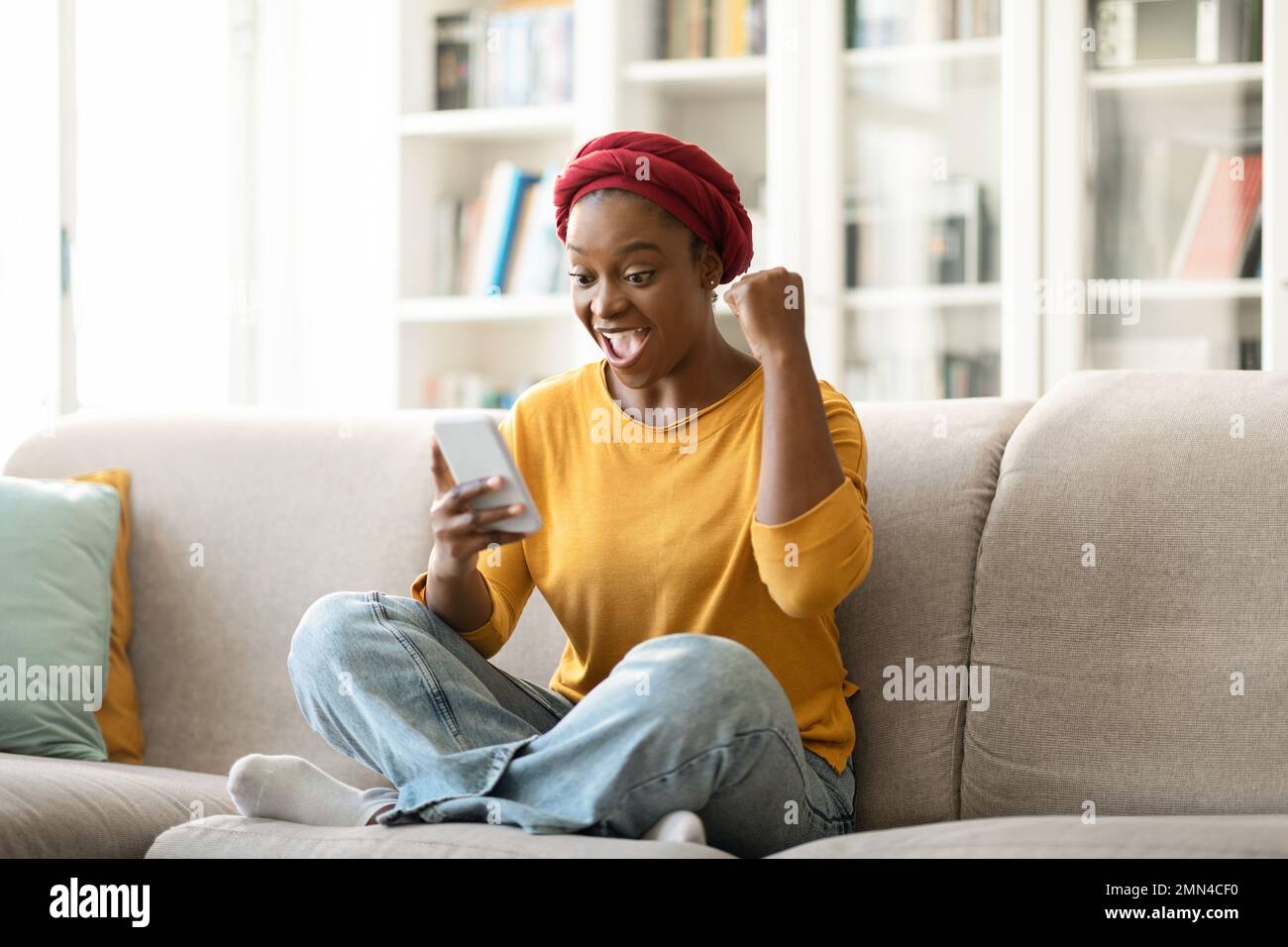 Happy african lady using phone and raising fist up Stock Photo - Alamy