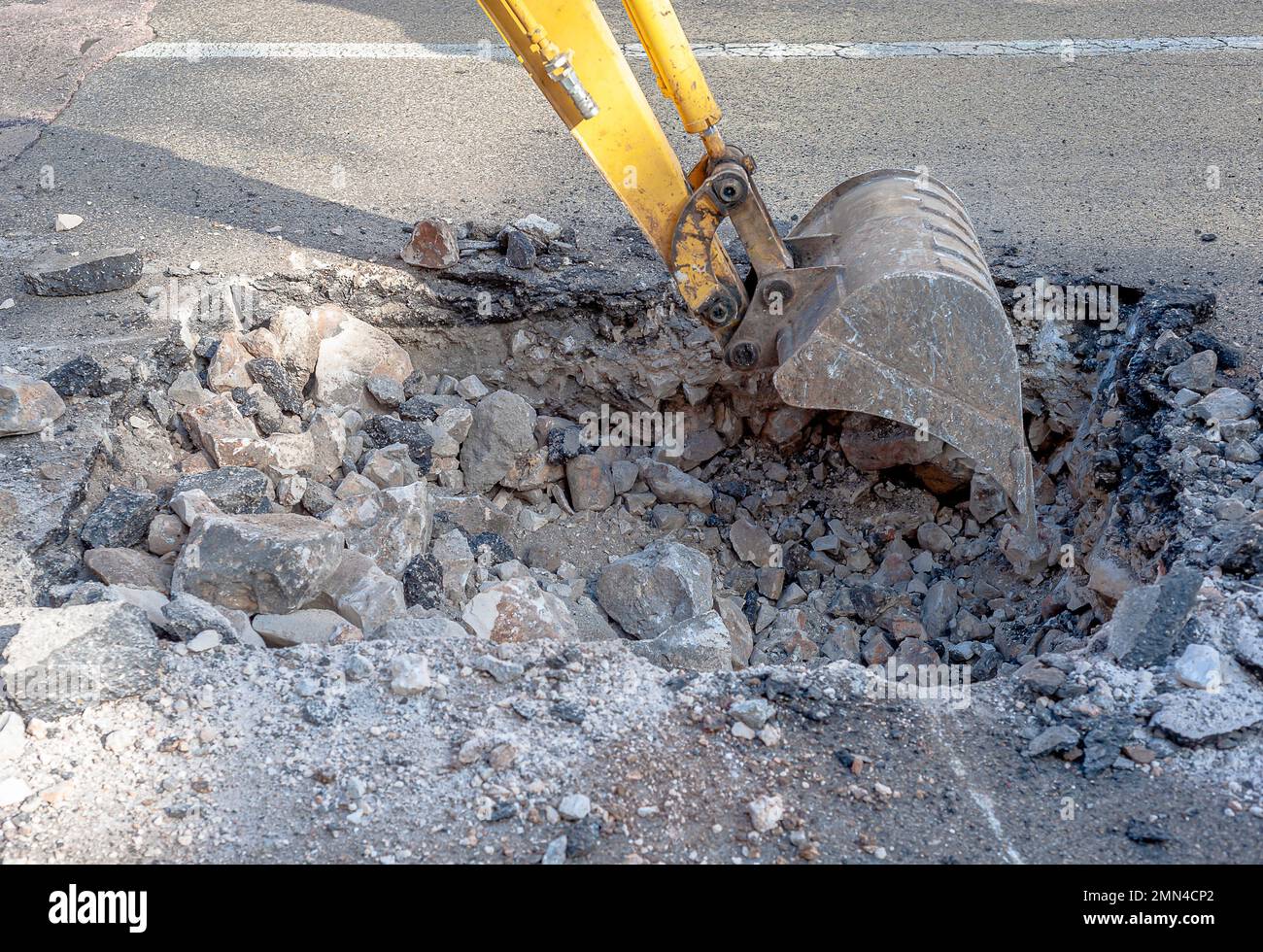 Dig asphalt with a tractor bucket. Tracked excavator on the street ...