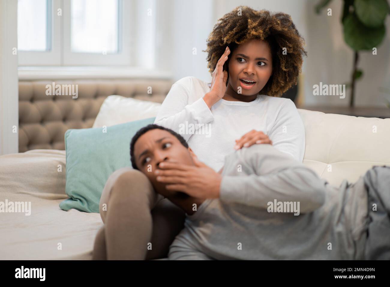 Shocked black couple watching horror at home Stock Photo - Alamy