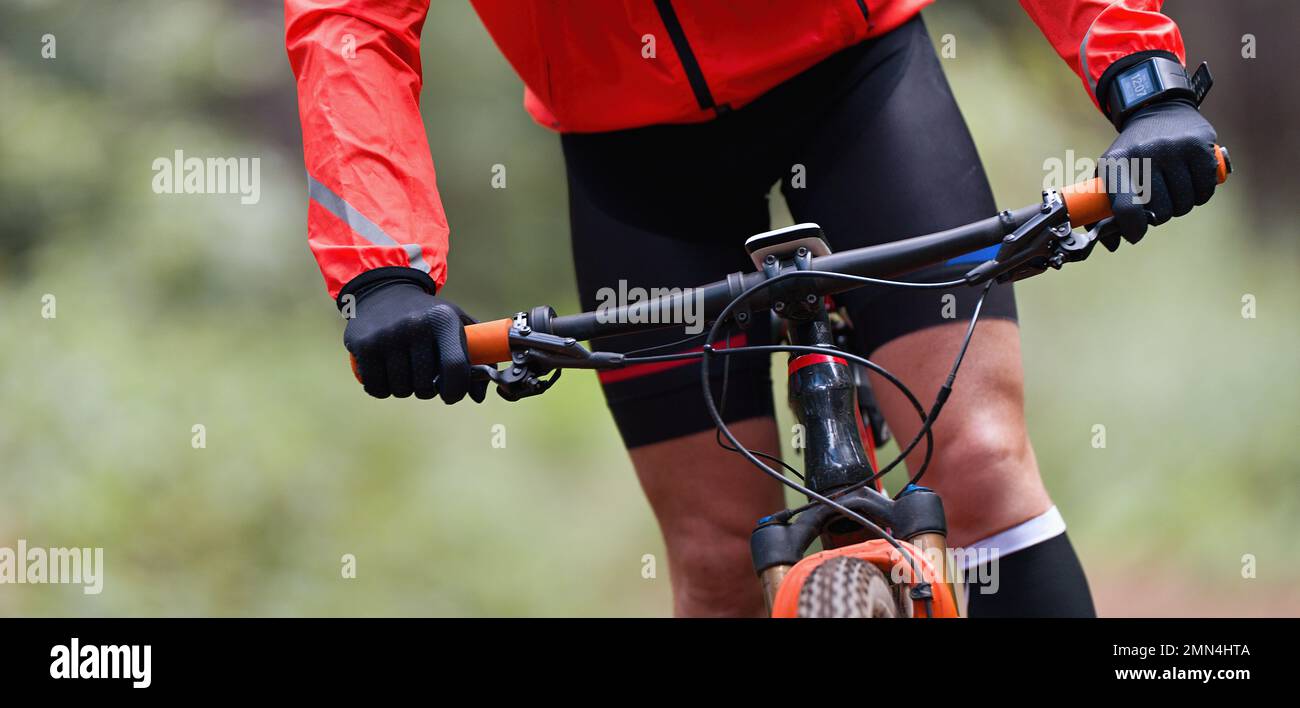 Mountain biker riding on bike singletrack trail, detail handlebars ...