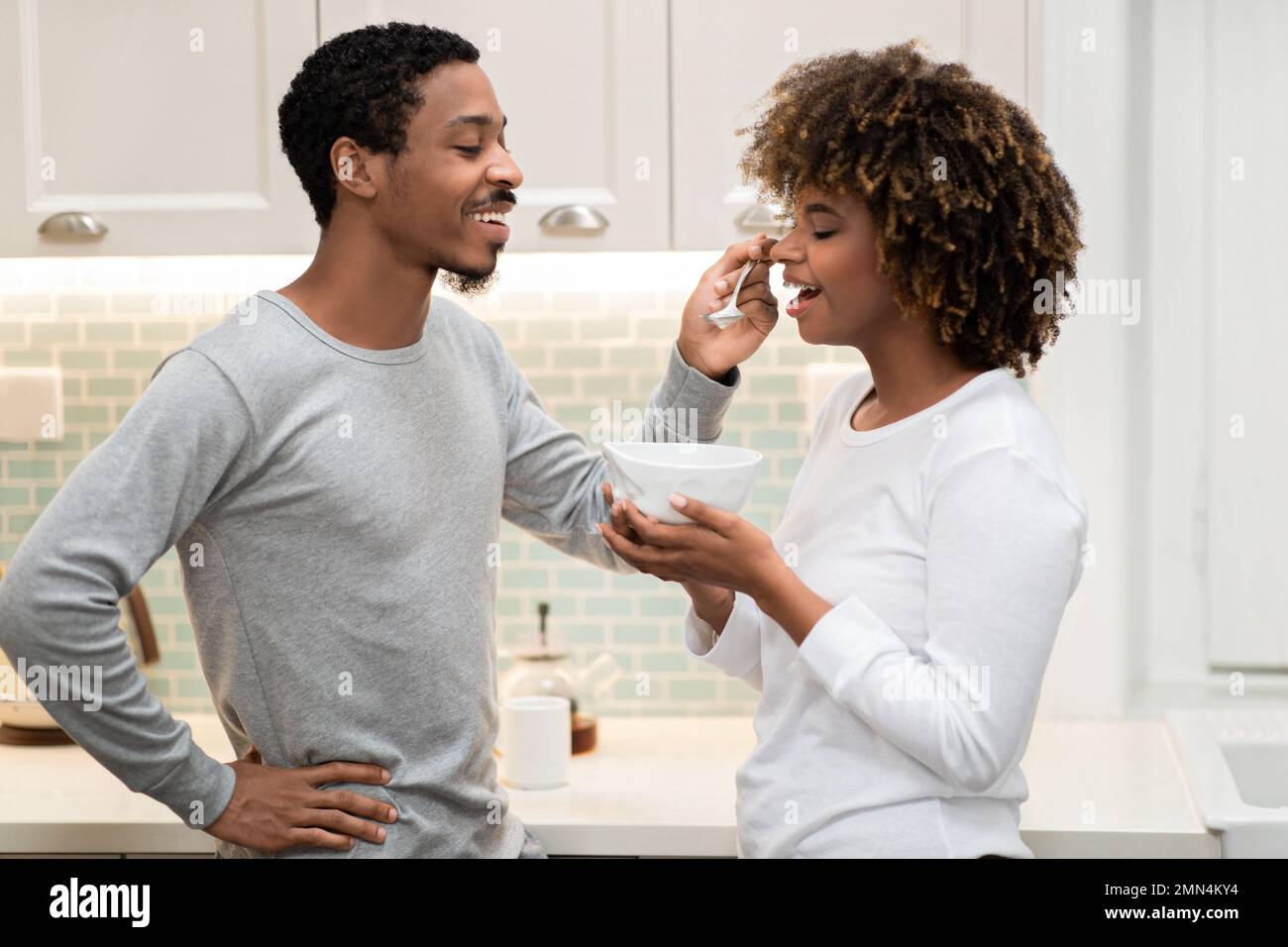 Loving black man feeding his pretty wife at home Stock Photo - Alamy