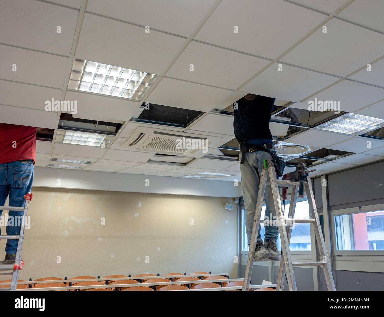 Construction worker assemble a suspended ceiling with drywall and ...