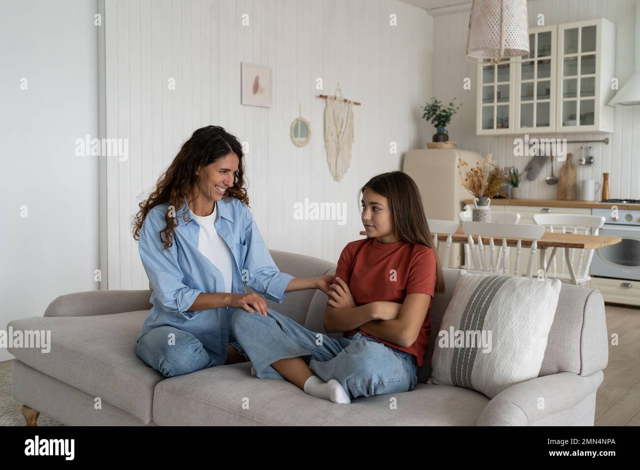 Shy introverted teenage girl sits in closed position on couch with ...