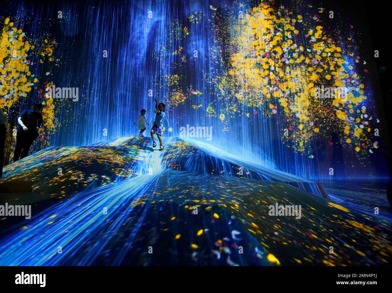 Children play on an installation that features projection of waterfall ...