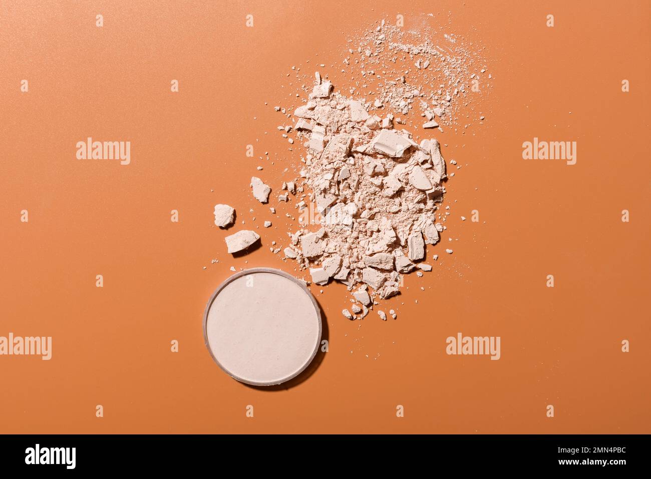Crushed face powder heap and round box of pressed one on brown ...