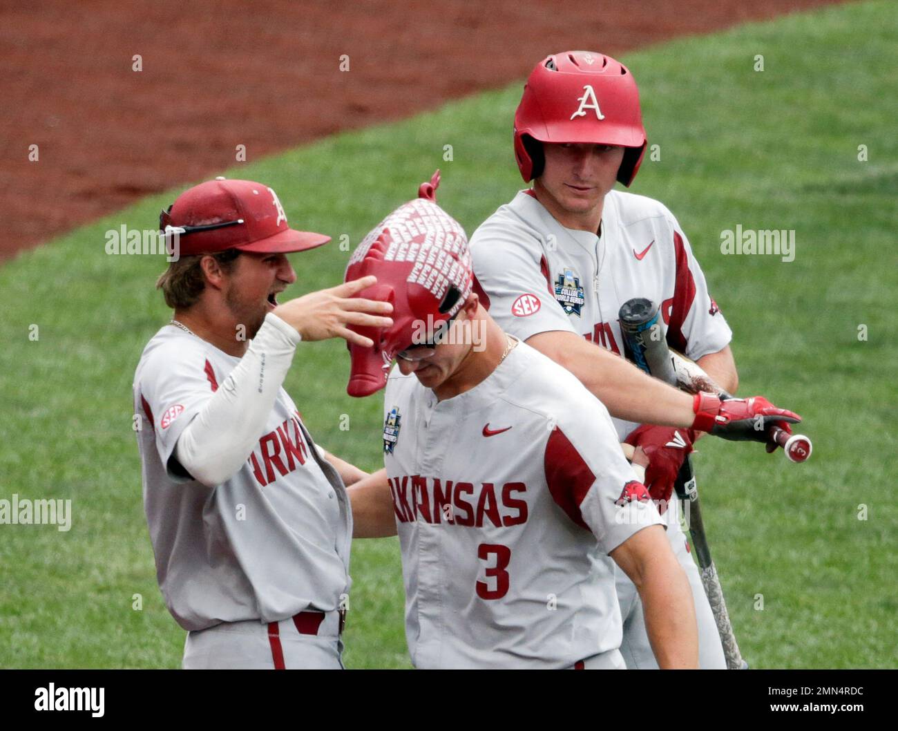 Arkansas' Jared Gates (3) is greeted at the dugout by Hunter Wilson ...