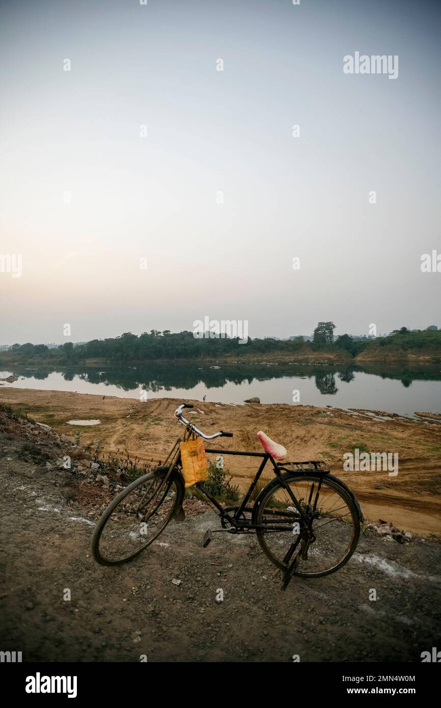 A villagers cycle standing alone by the side of River Subarnarekha ...