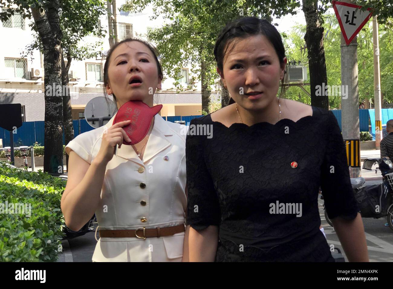 North Koreans, wearing the pins of their leaders, walk away after ...
