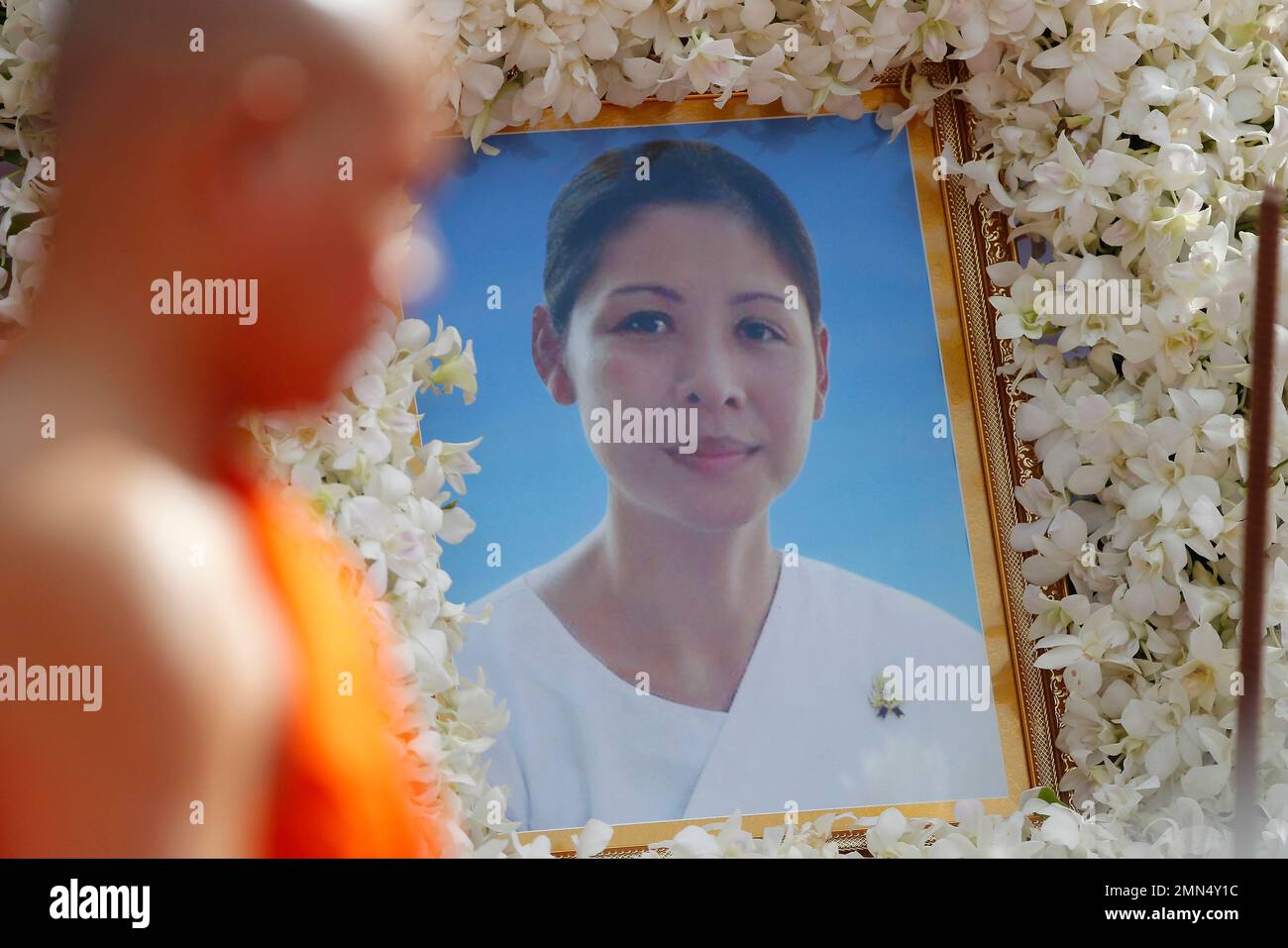 A Buddhist monk leads a funeral procession past a portrait photo of Ouk Phalla, Prince Norodom ...