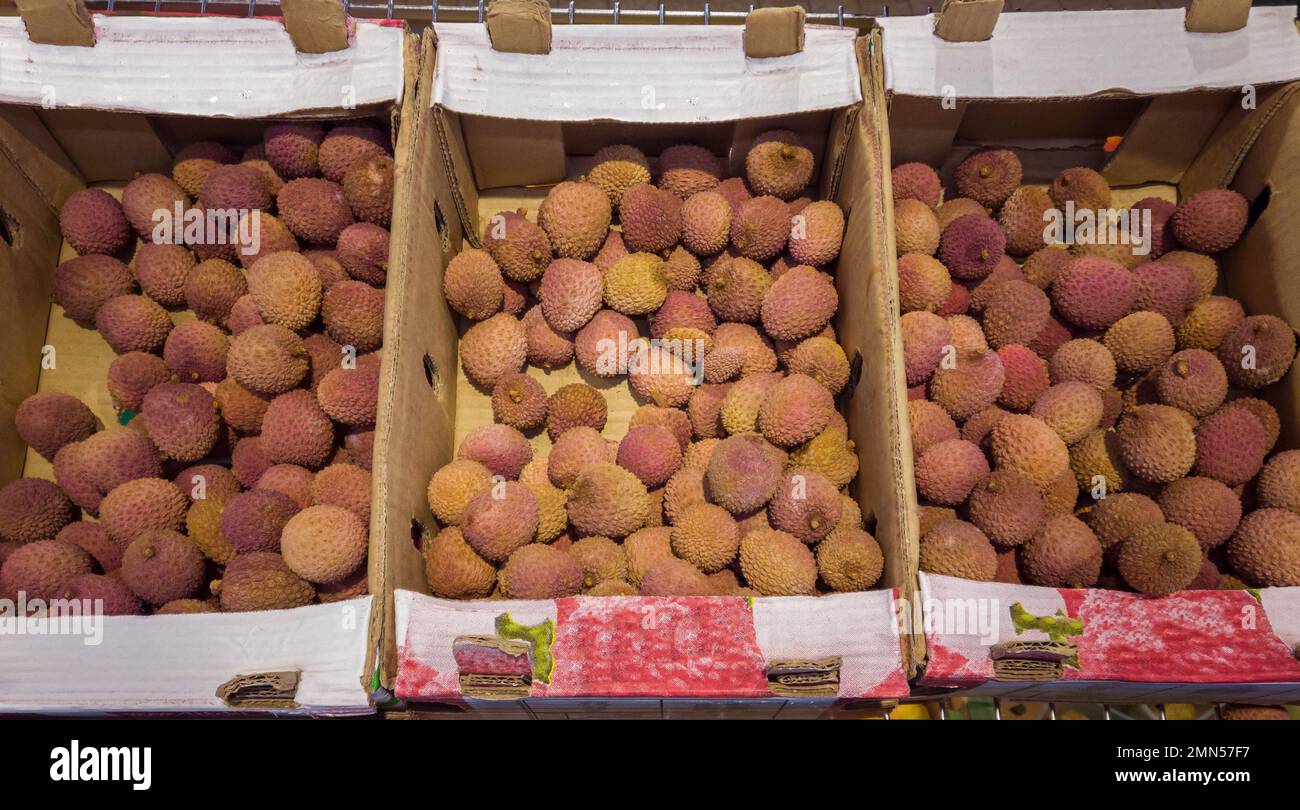 litchi fruits or lychee in cardboard boxes on the greengrocer's stall ...