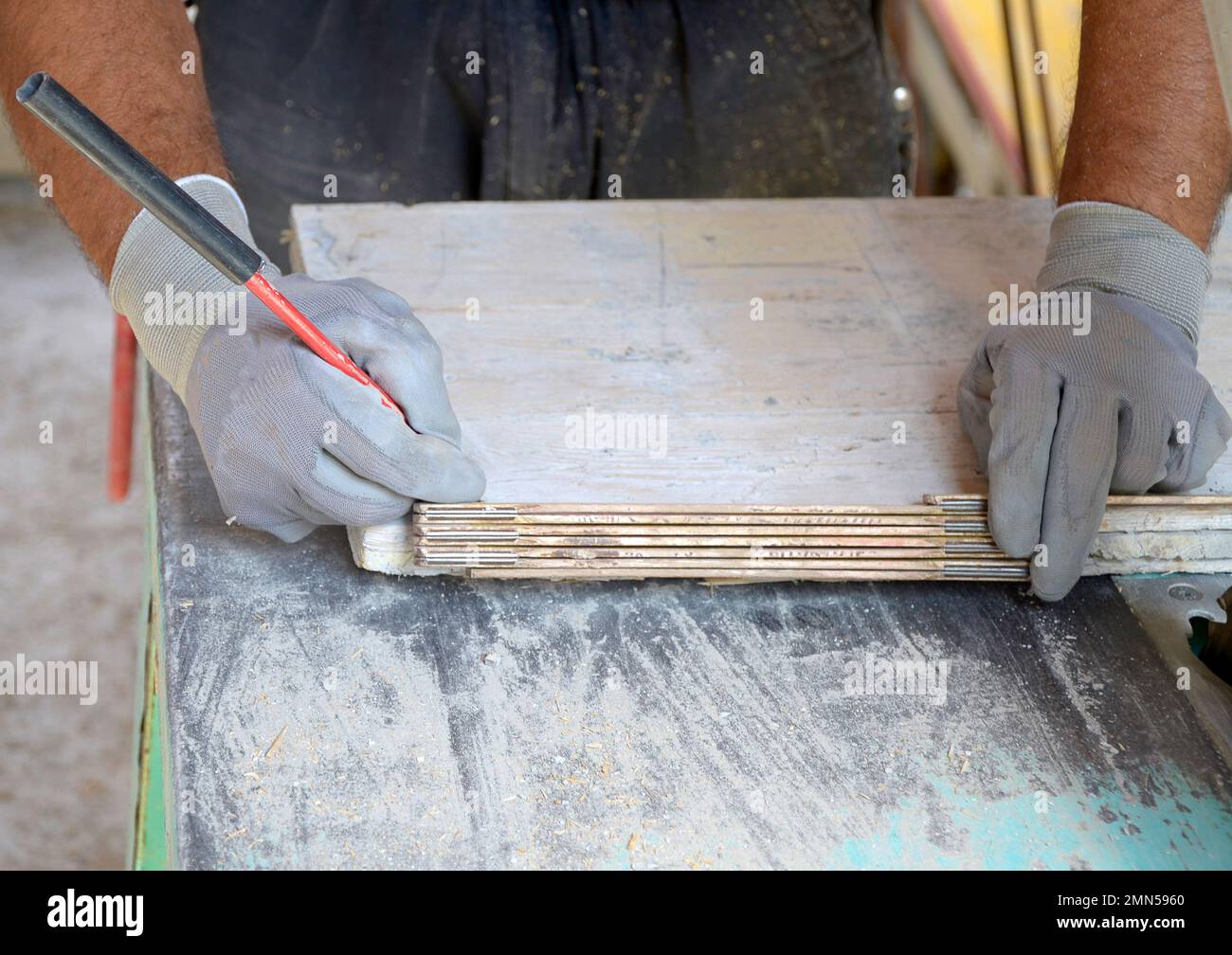 Construction carpenter measures and puts a pencil mark on a wooden ...