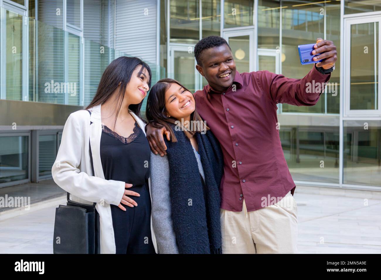 Attractive coworkers taking a selfie with a smartphone outside the ...