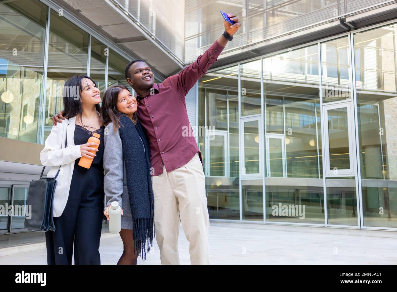 Attractive coworkers taking a selfie with a smartphone outside the ...